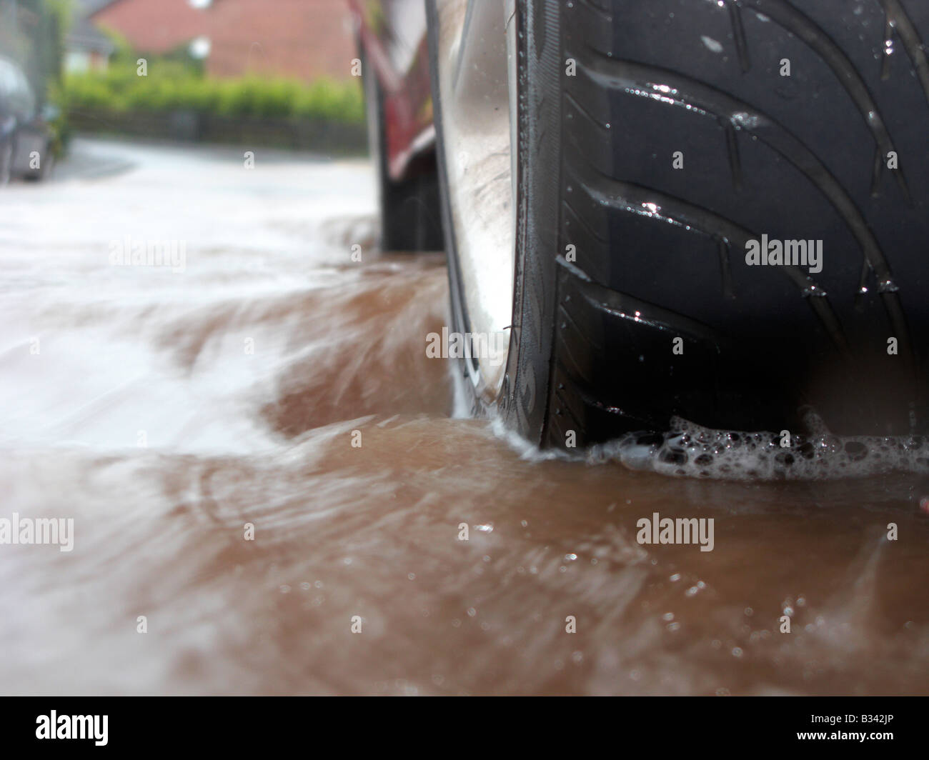 rain and river overflow flooding a street past car tyre and alloy wheel ...