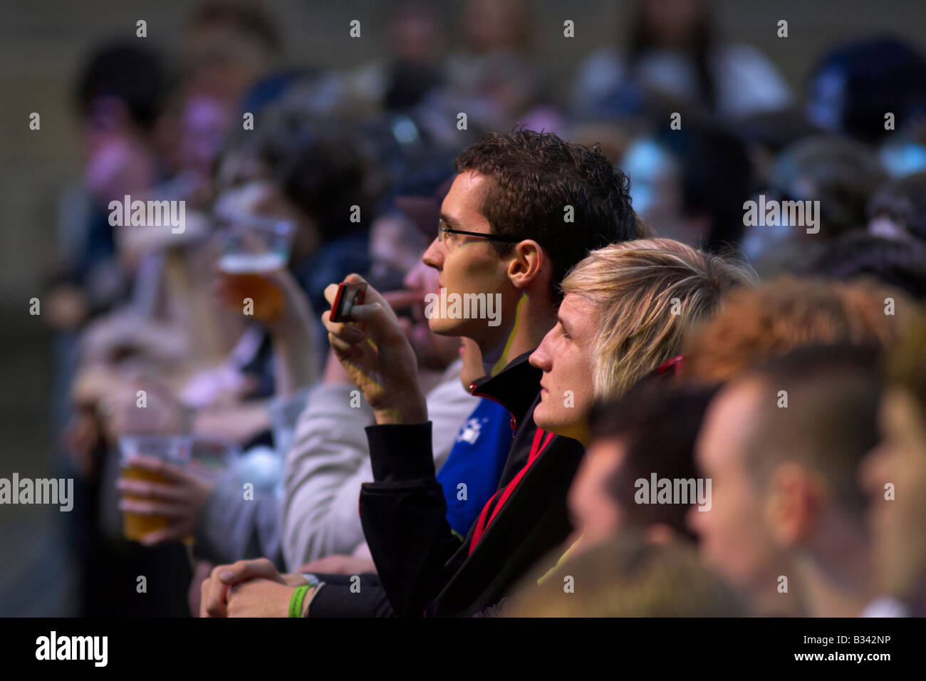 young man with mobile phone filming in the front row of a concert in ...
