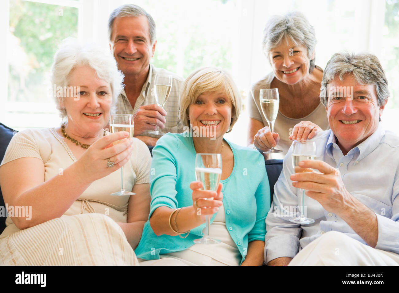 Five friends in living room drinking champagne and smiling Stock Photo ...