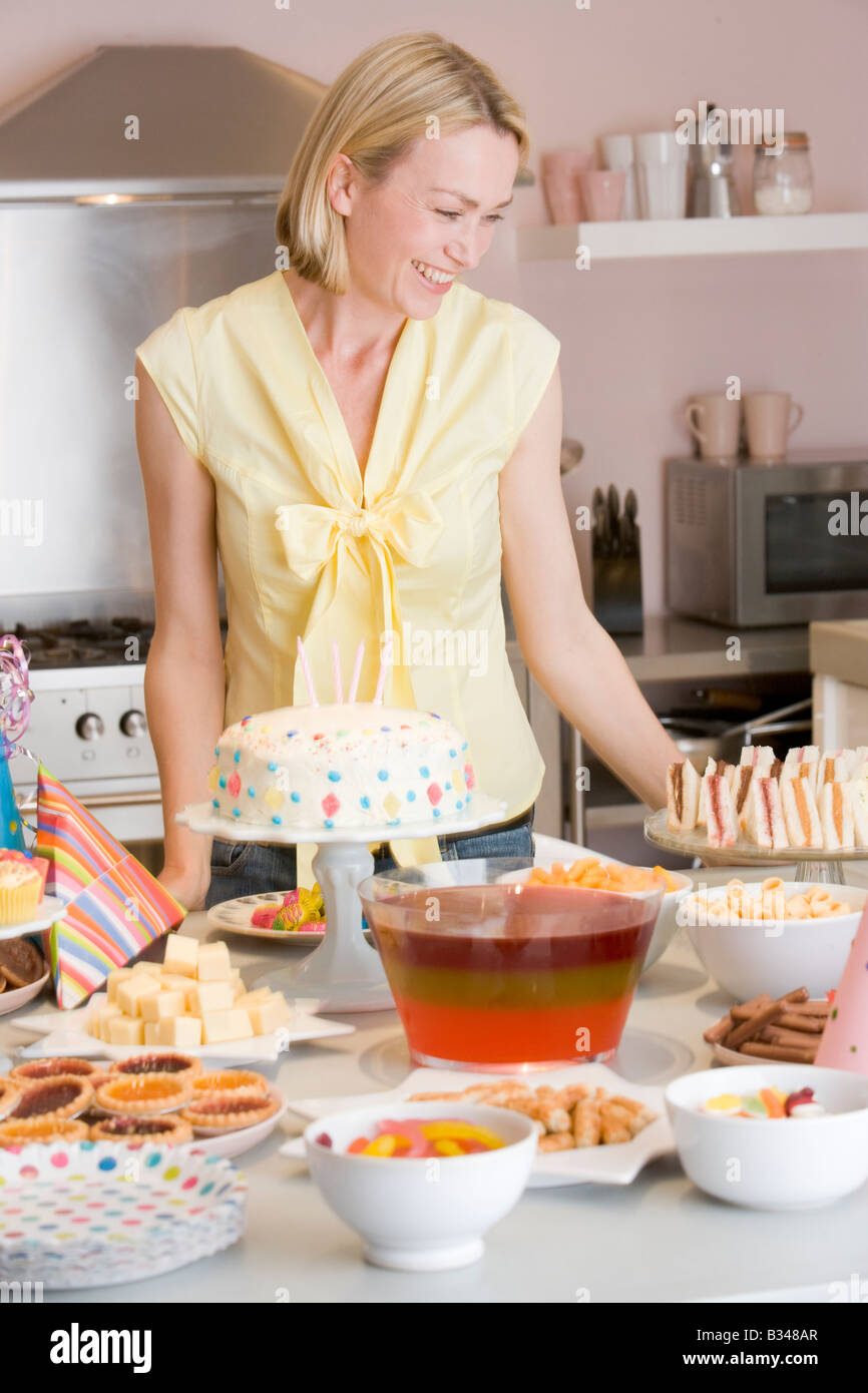 Woman at party standing by food table smiling Stock Photo - Alamy