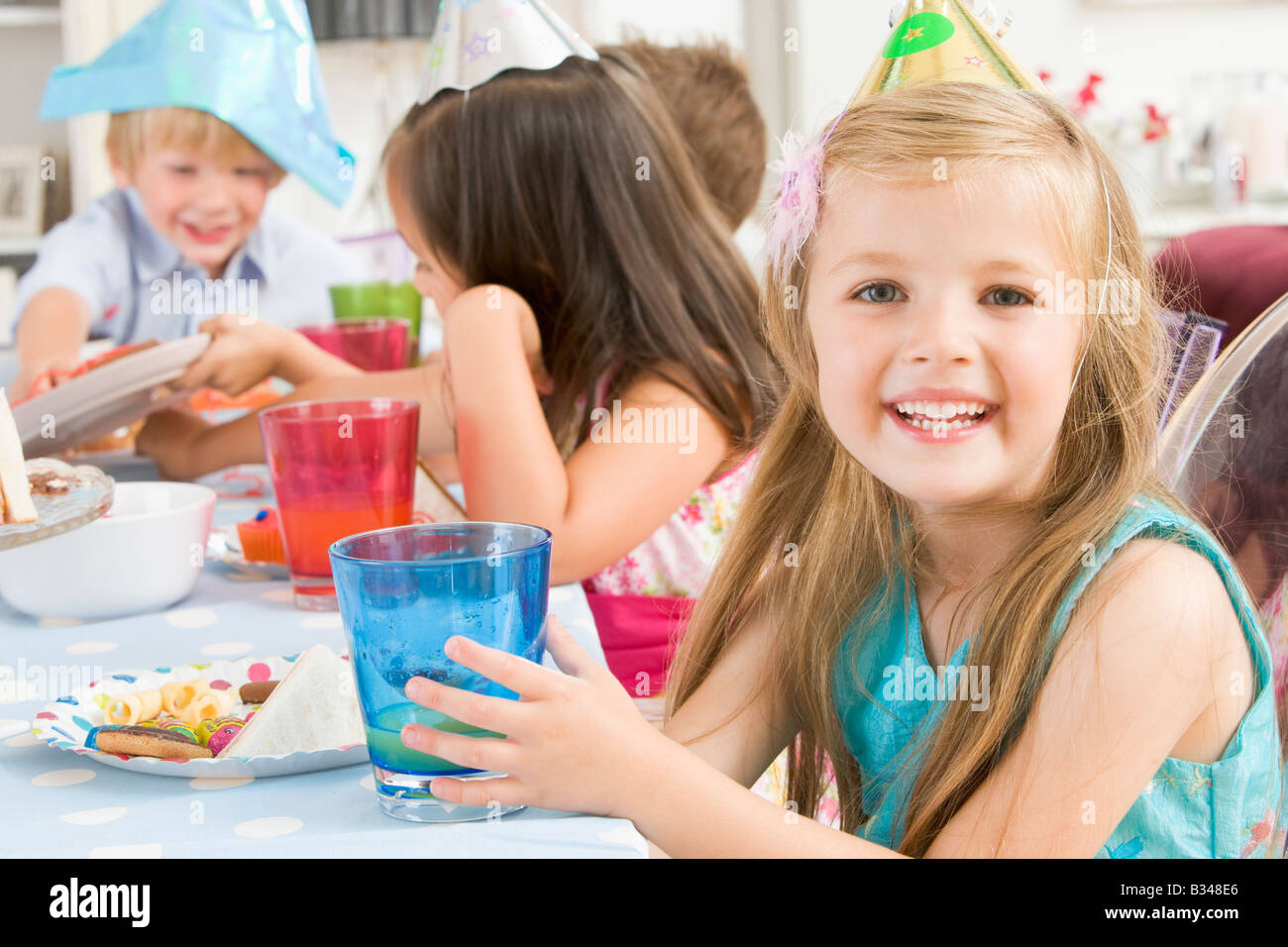 Young girl at party sitting at table with food smiling Stock Photo - Alamy