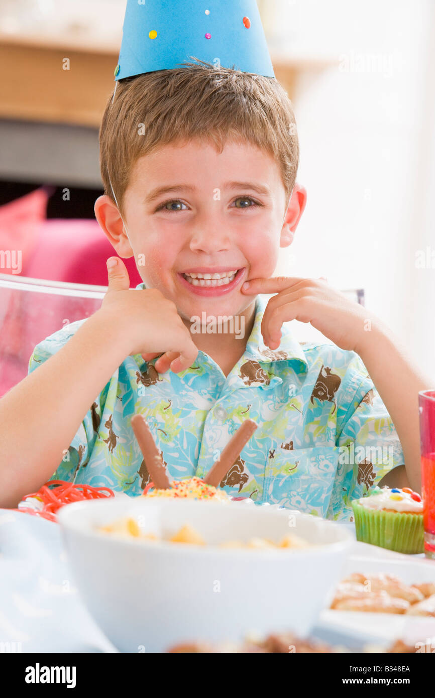 Young boy at party sitting at table with food smiling Stock Photo - Alamy
