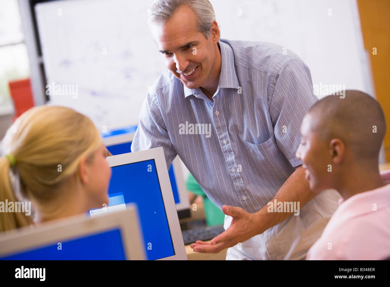 Teacher with students in computer class Stock Photo - Alamy