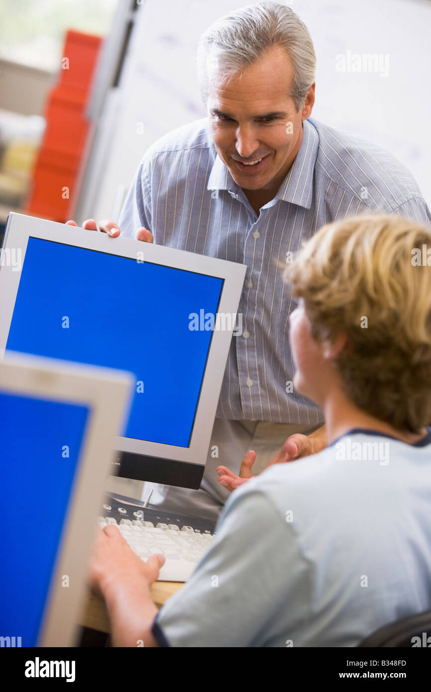 Teacher with male student in computer class Stock Photo - Alamy