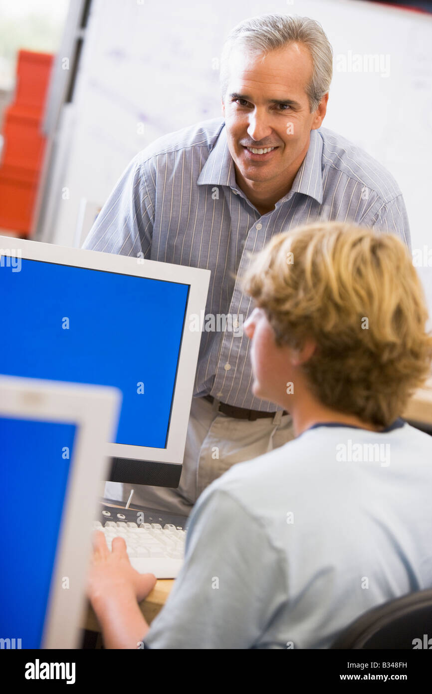 Teacher with male student in computer class Stock Photo - Alamy