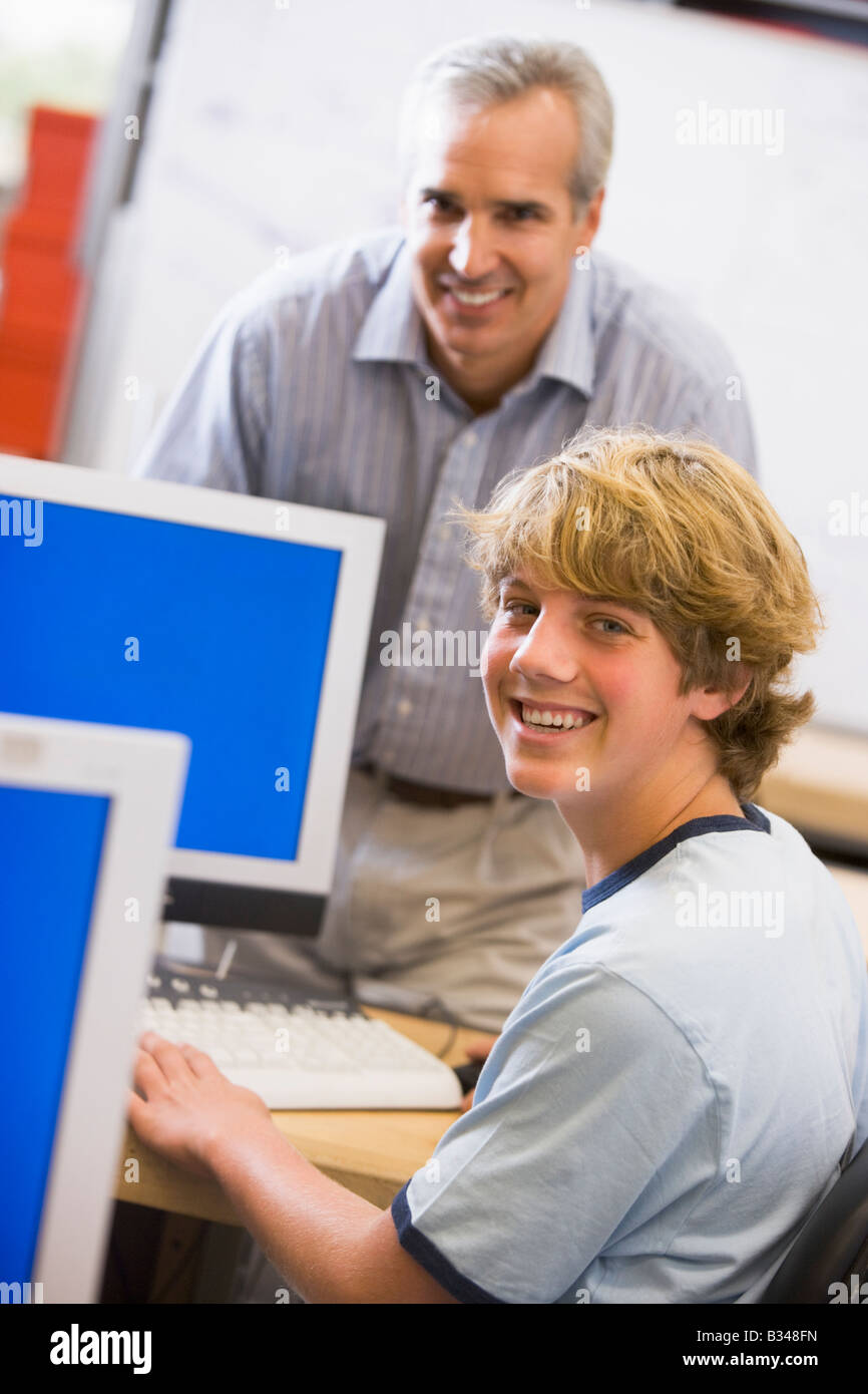 Teacher with male student in computer class Stock Photo - Alamy