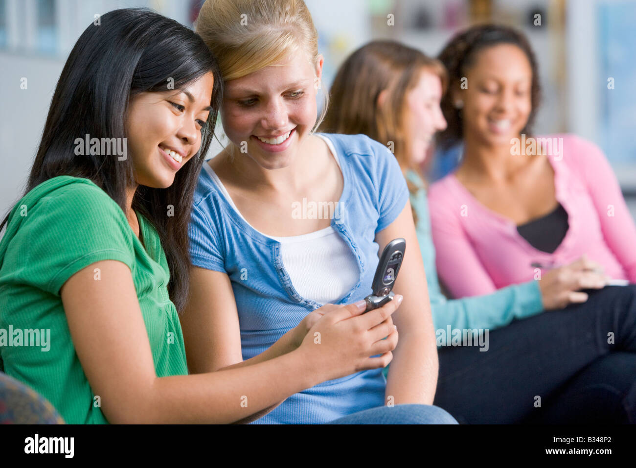 Female students looking at a mobile phone Stock Photo - Alamy