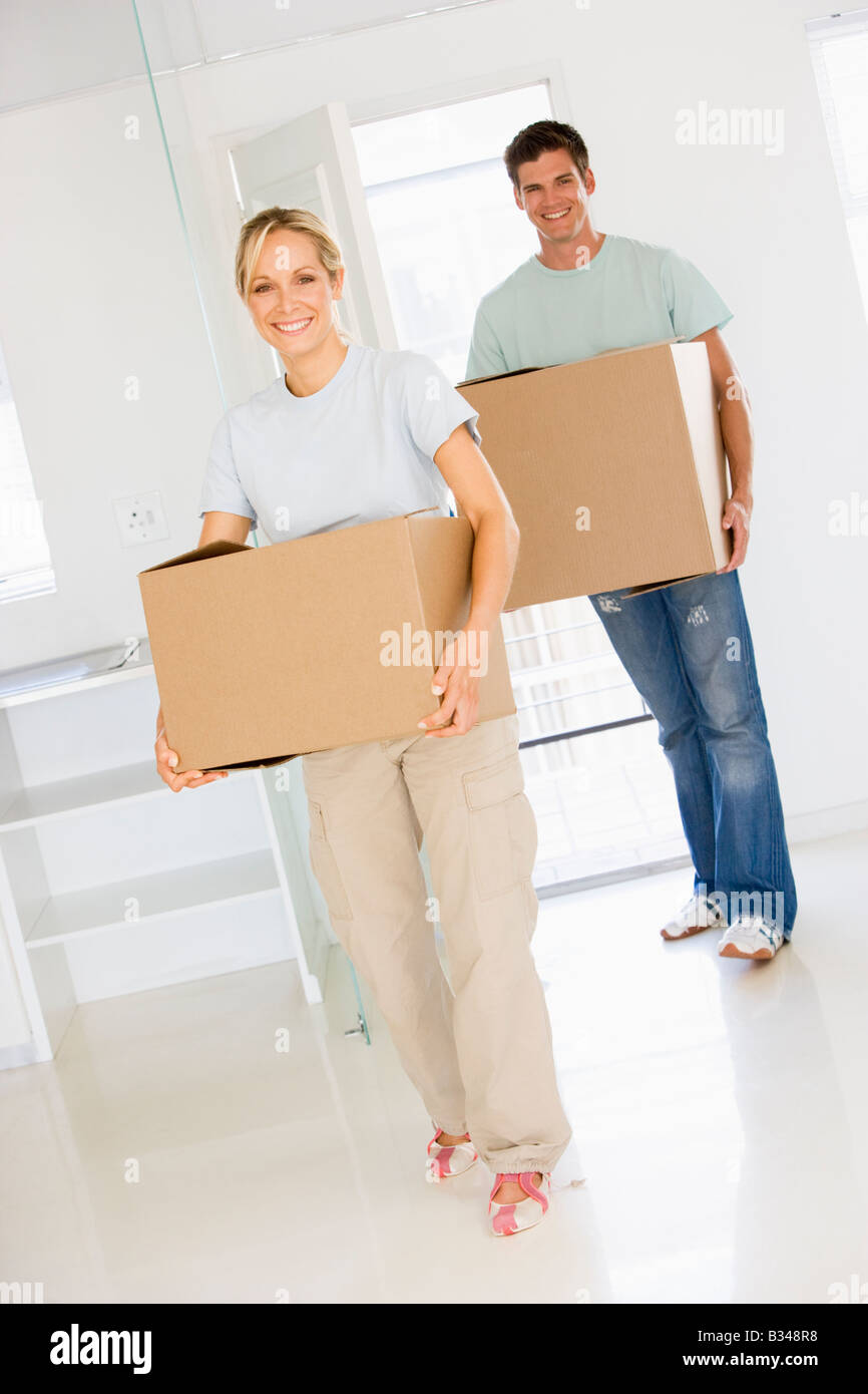Couple with boxes moving into new home smiling Stock Photo - Alamy
