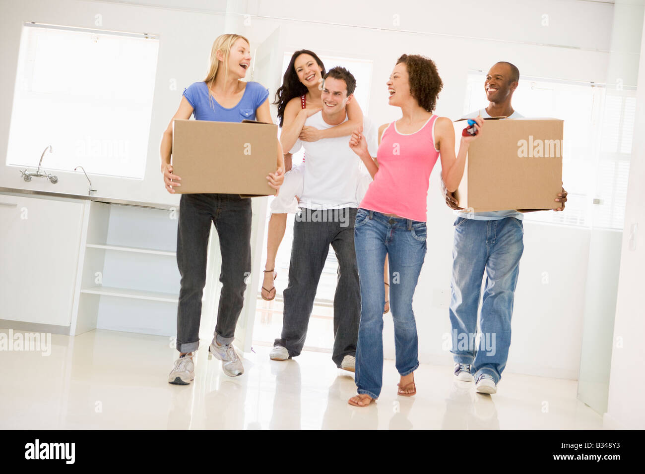 Group of friends moving into new home smiling Stock Photo - Alamy