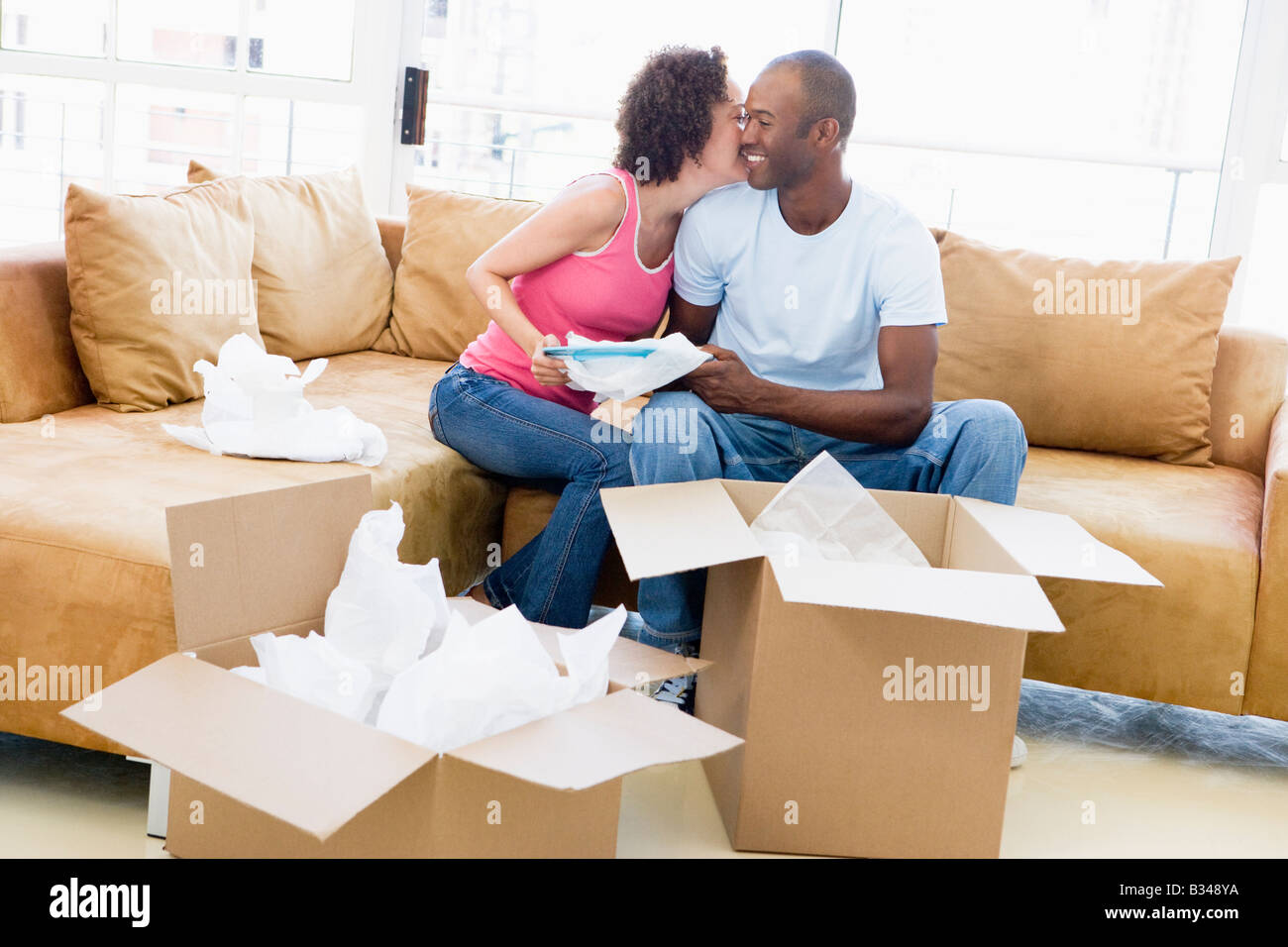 Couple unpacking boxes in new home kissing and smiling Stock Photo - Alamy