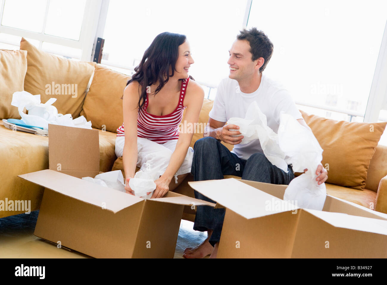 Couple unpacking boxes in new home smiling Stock Photo - Alamy