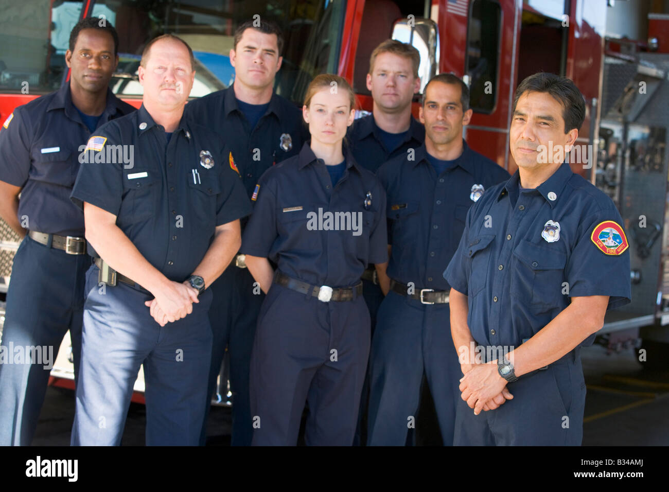 Six firefighters standing in front of fire engine with captain (depth ...