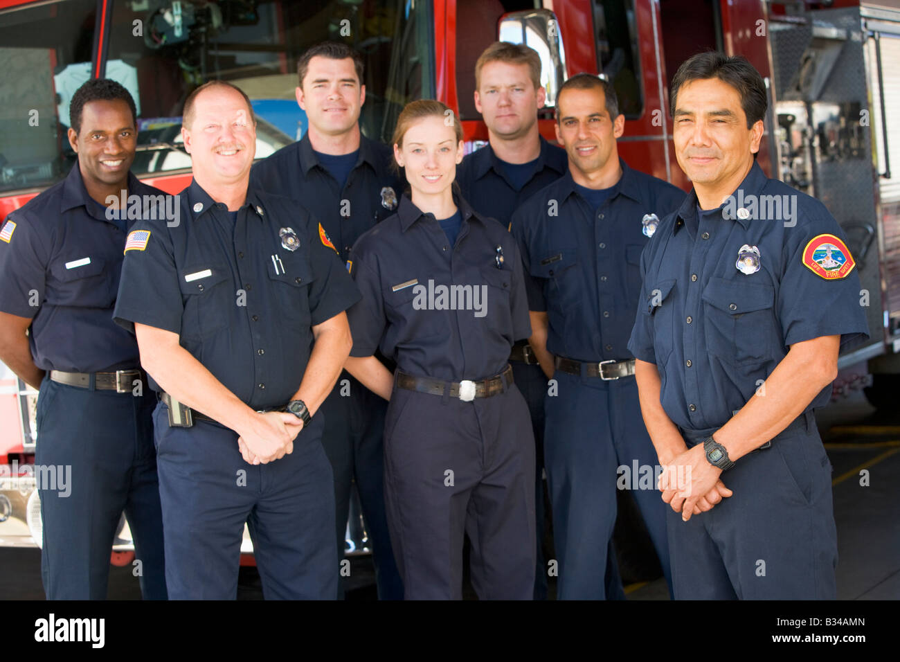 Six firefighters standing in front of fire engine with captain (depth ...