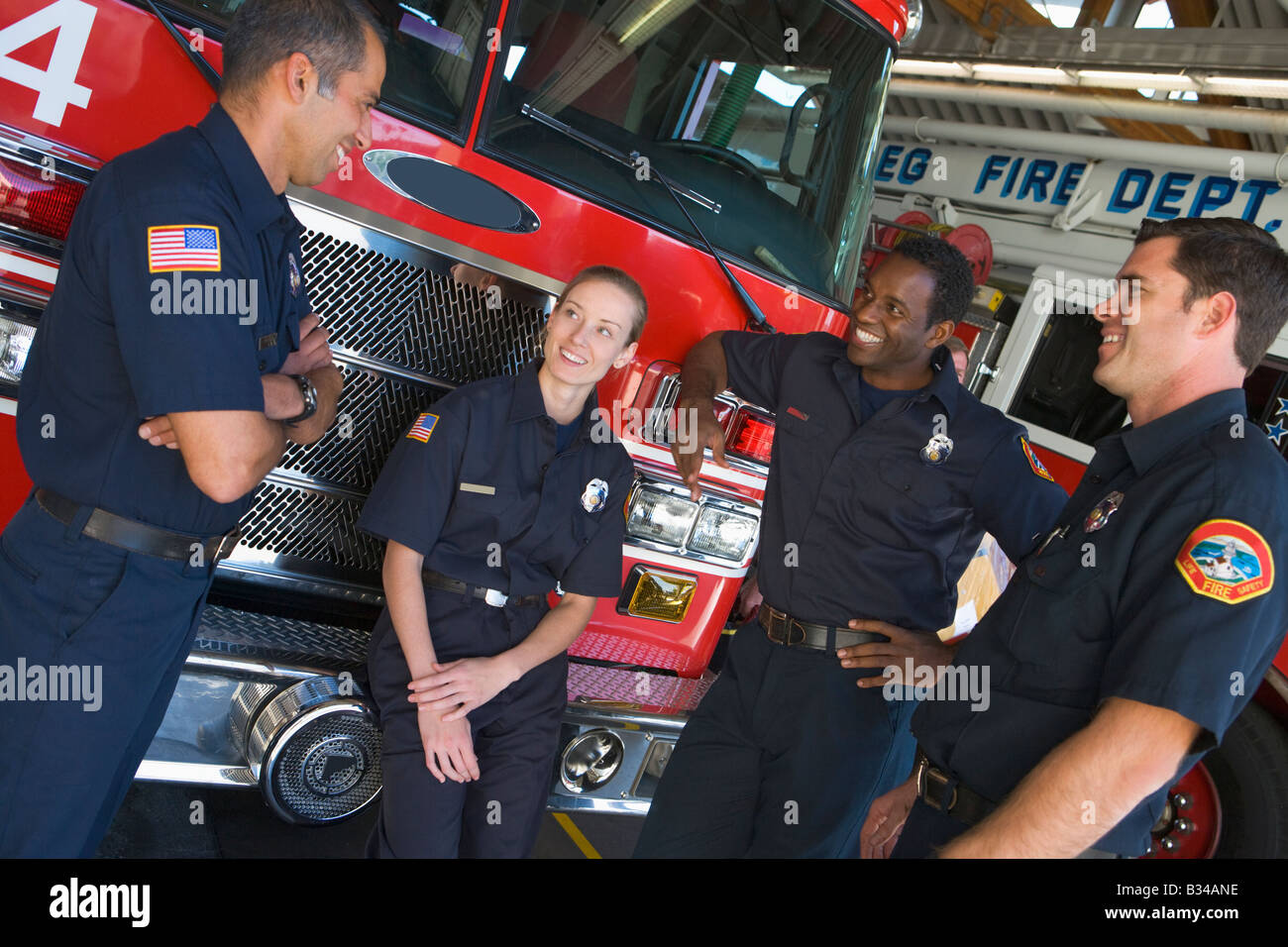 Four firefighters talking by fire engine Stock Photo - Alamy