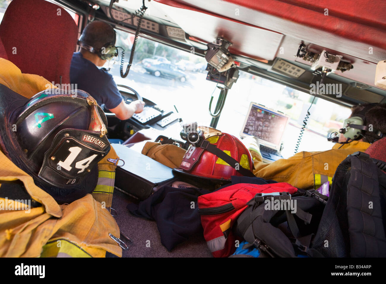 Two firefighters driving a fire engine with gear in the back (selective ...