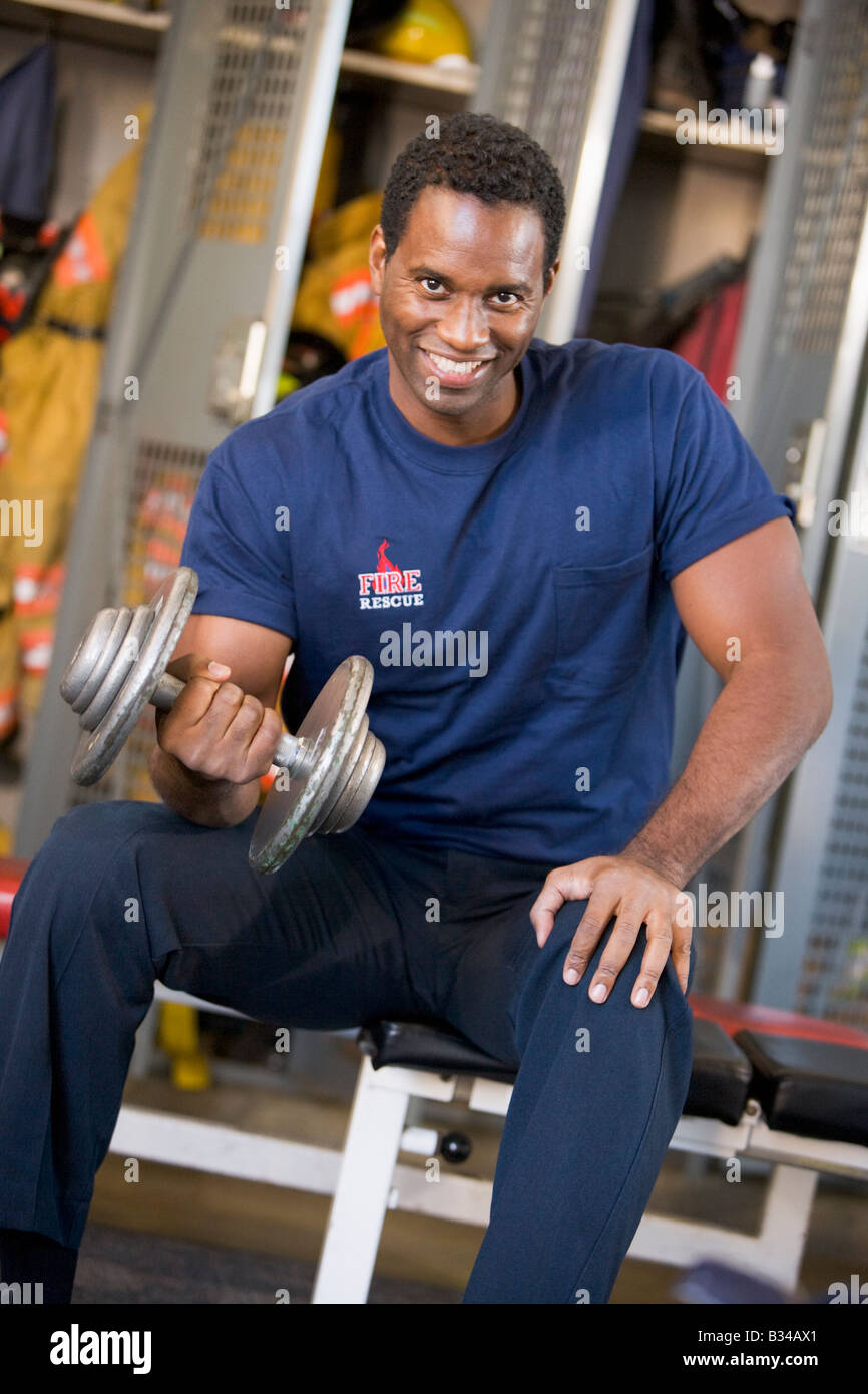 Fireman lifting dumbbell on bench in fire station locker room Stock ...