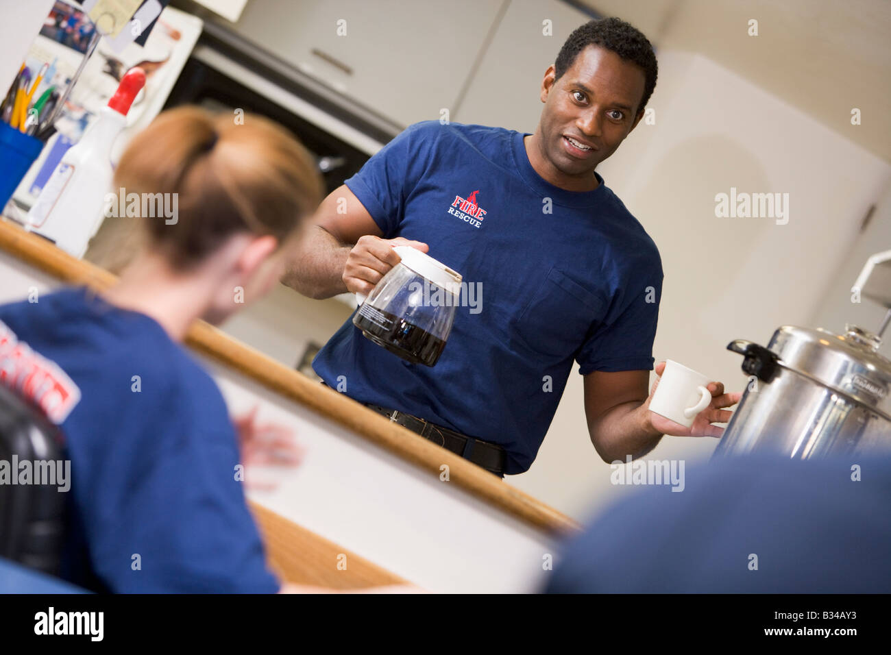 Three firefighters in break room with one getting coffee (selective ...