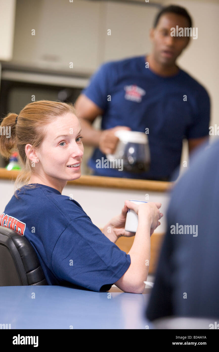 Three firefighters in break room with one getting coffee in background ...