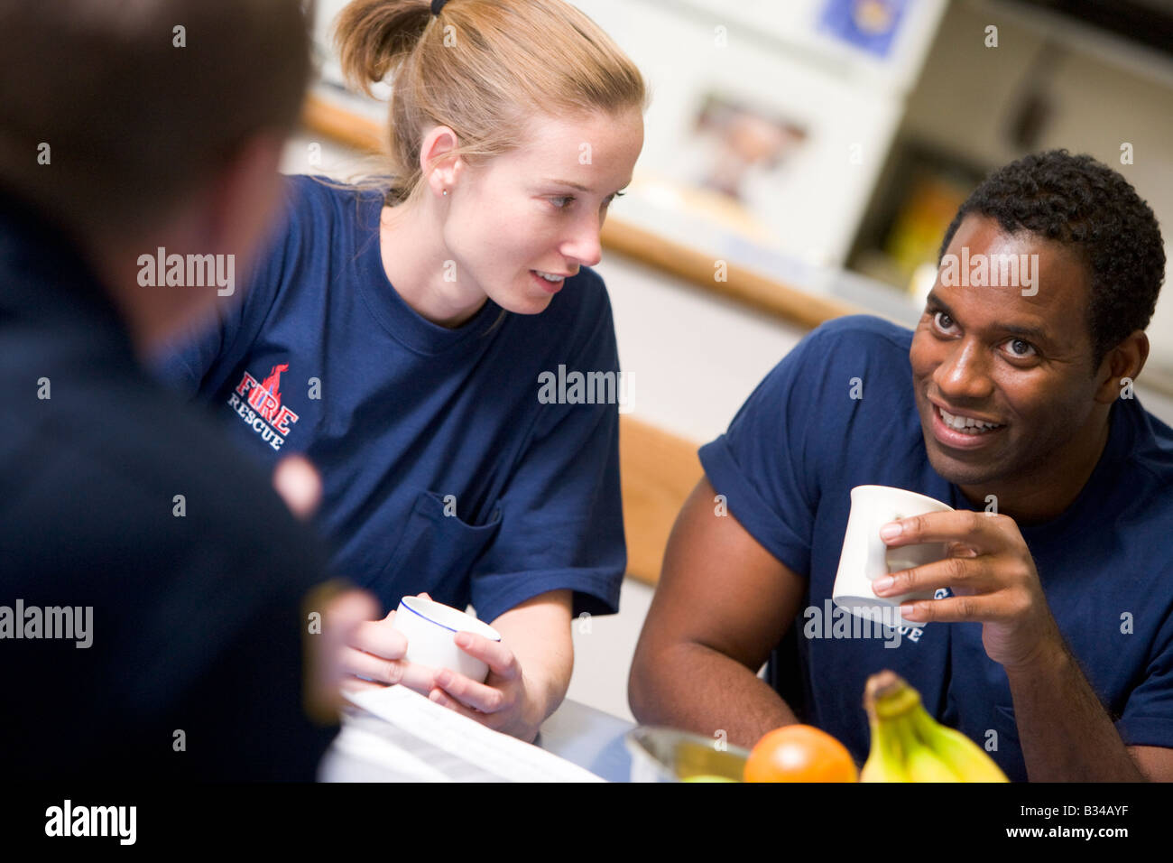Three firefighters in break room drinking coffee and talking (selective ...