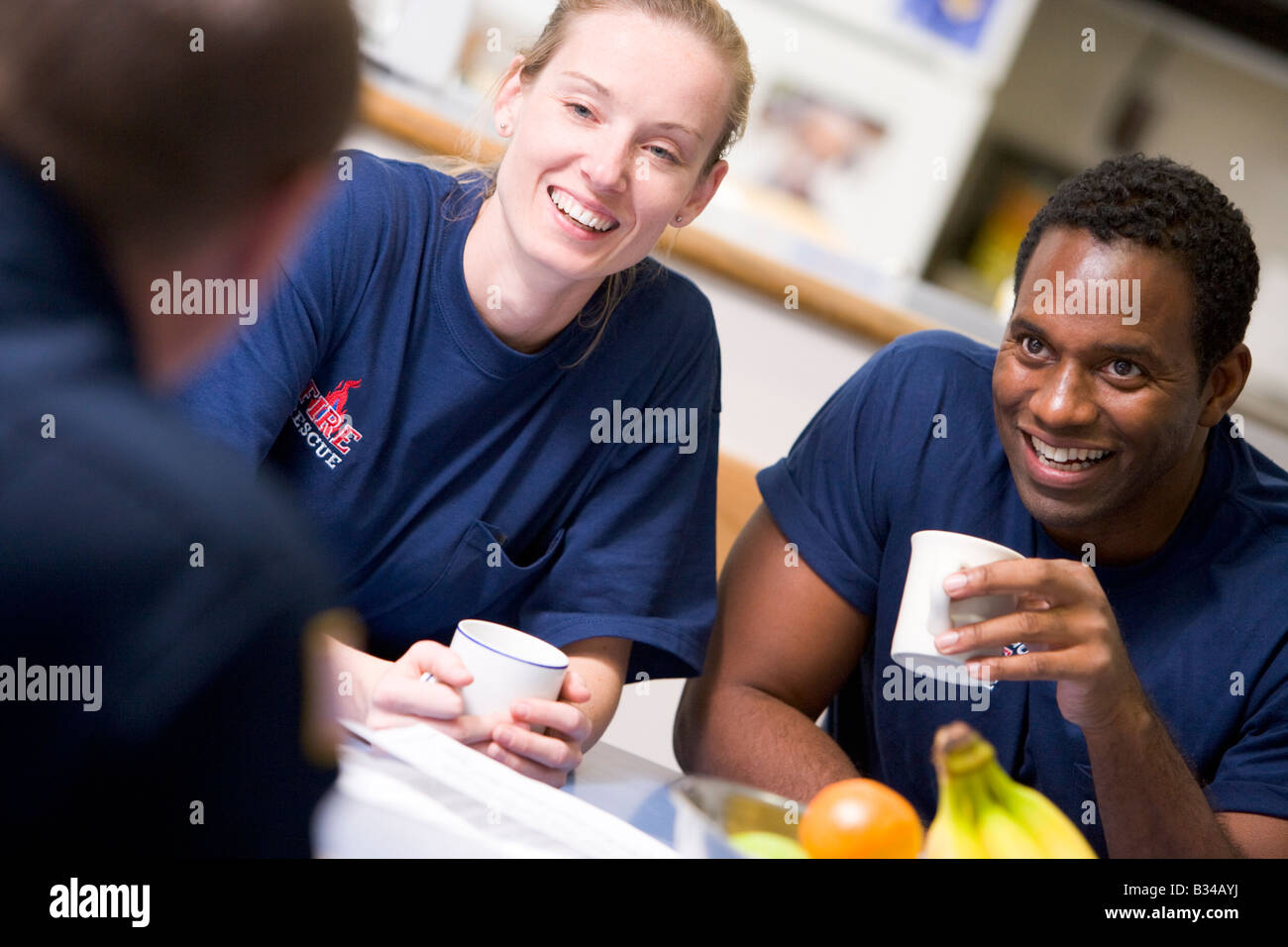 Three firefighters in break room drinking coffee and talking (selective ...
