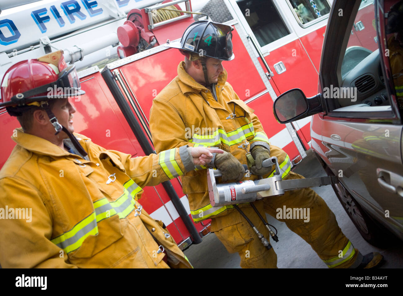 Two firemen using the jaws of life on a car door Stock Photo - Alamy