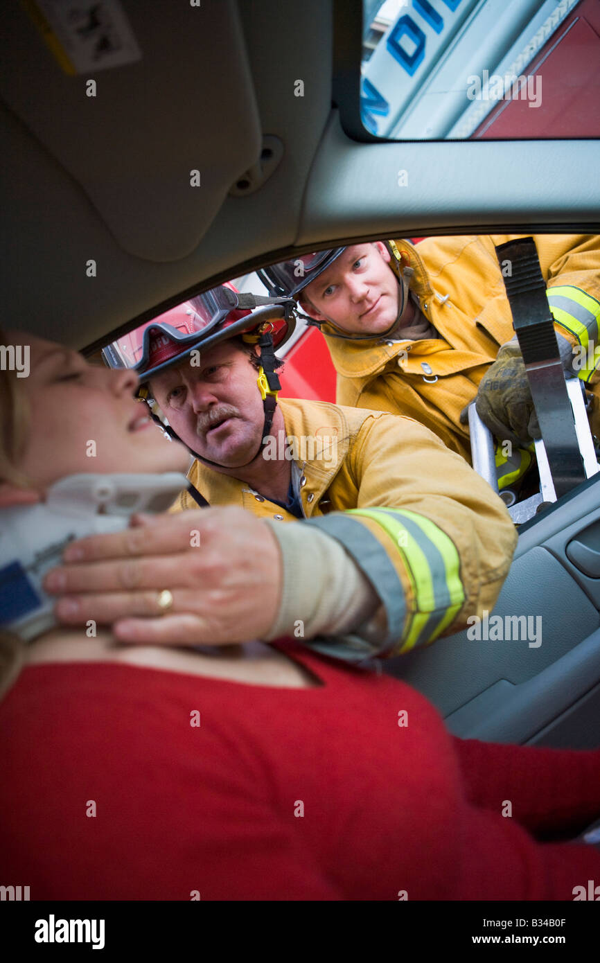 Fireman helping woman with neck brace while another fireman uses the ...