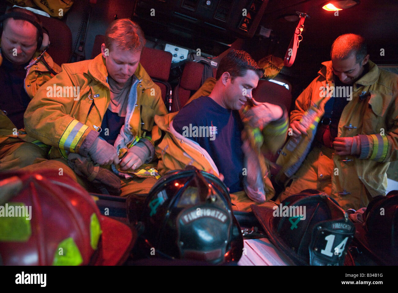 Four firemen in fire engine putting on gear (blur Stock Photo - Alamy