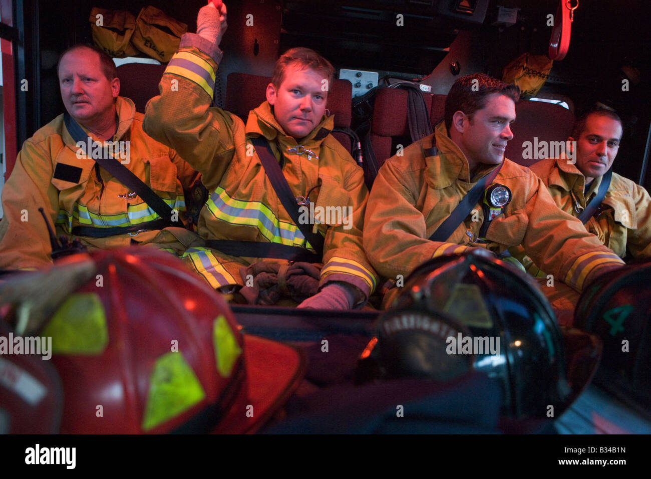Four firemen in fire engine with gear Stock Photo - Alamy