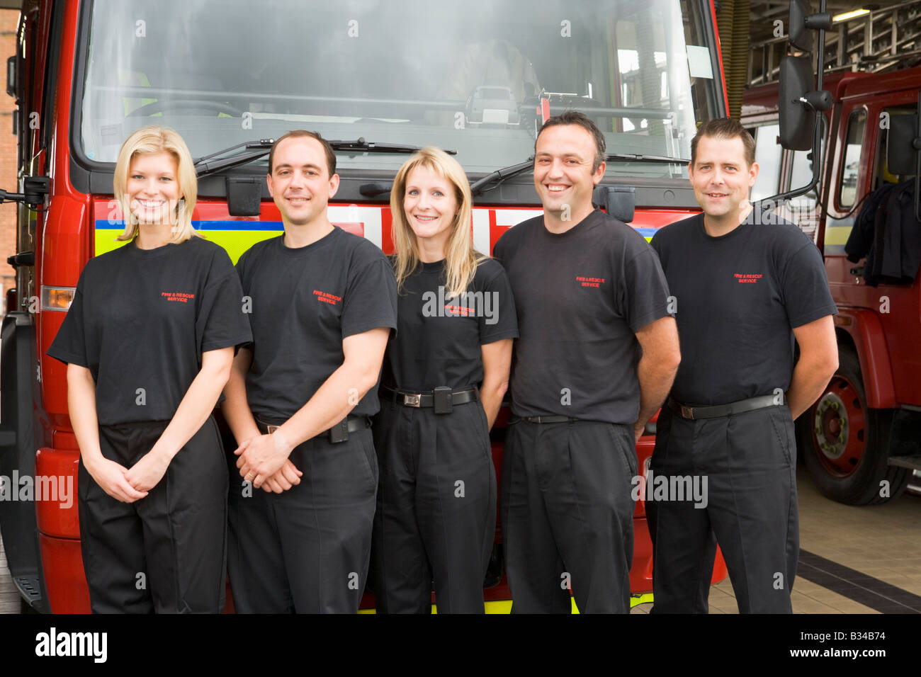 Five firefighters standing in front of fire engine Stock Photo - Alamy