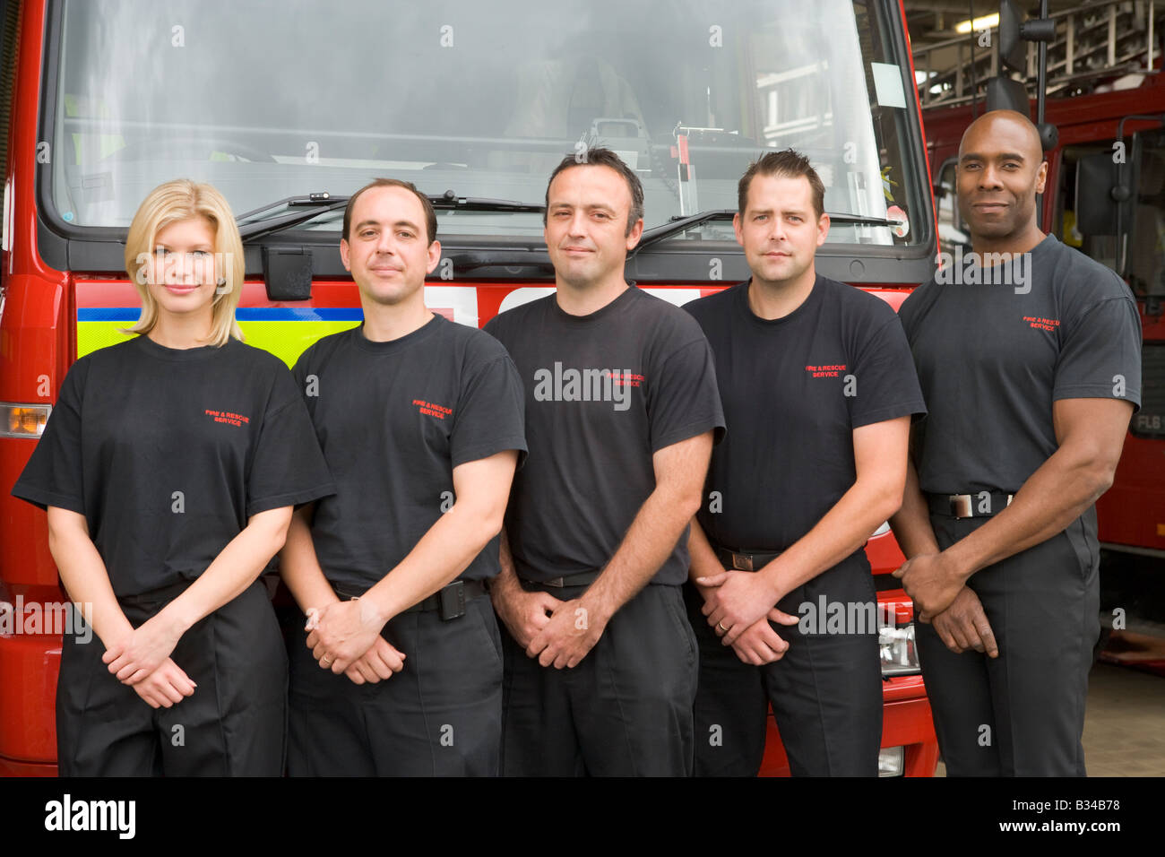 Five firefighters standing in front of fire engine Stock Photo - Alamy