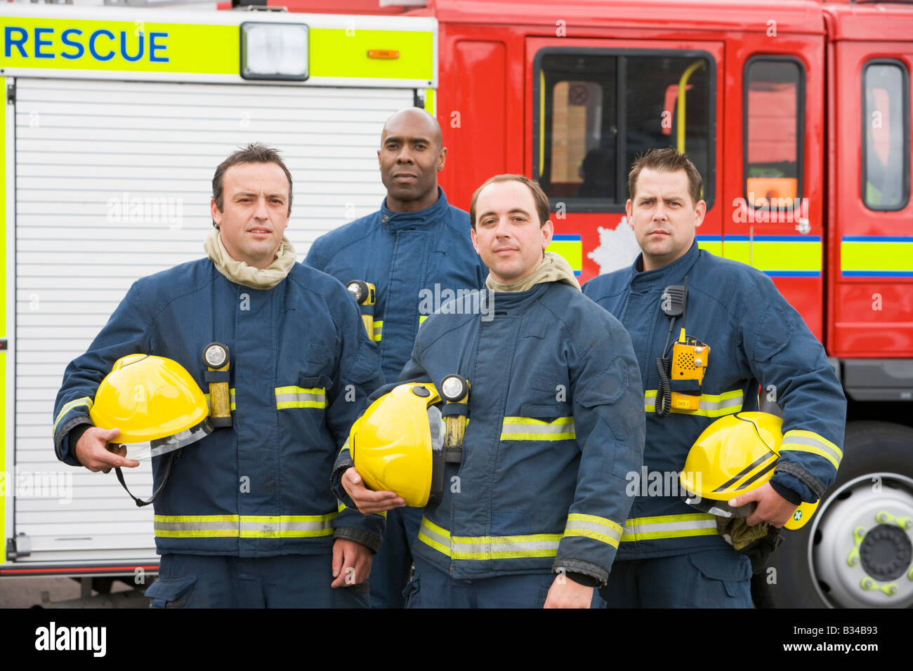 Four firefighters standing by fire engine Stock Photo - Alamy
