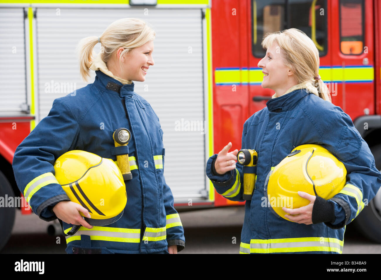 Two firewomen standing by fire engine talking Stock Photo - Alamy