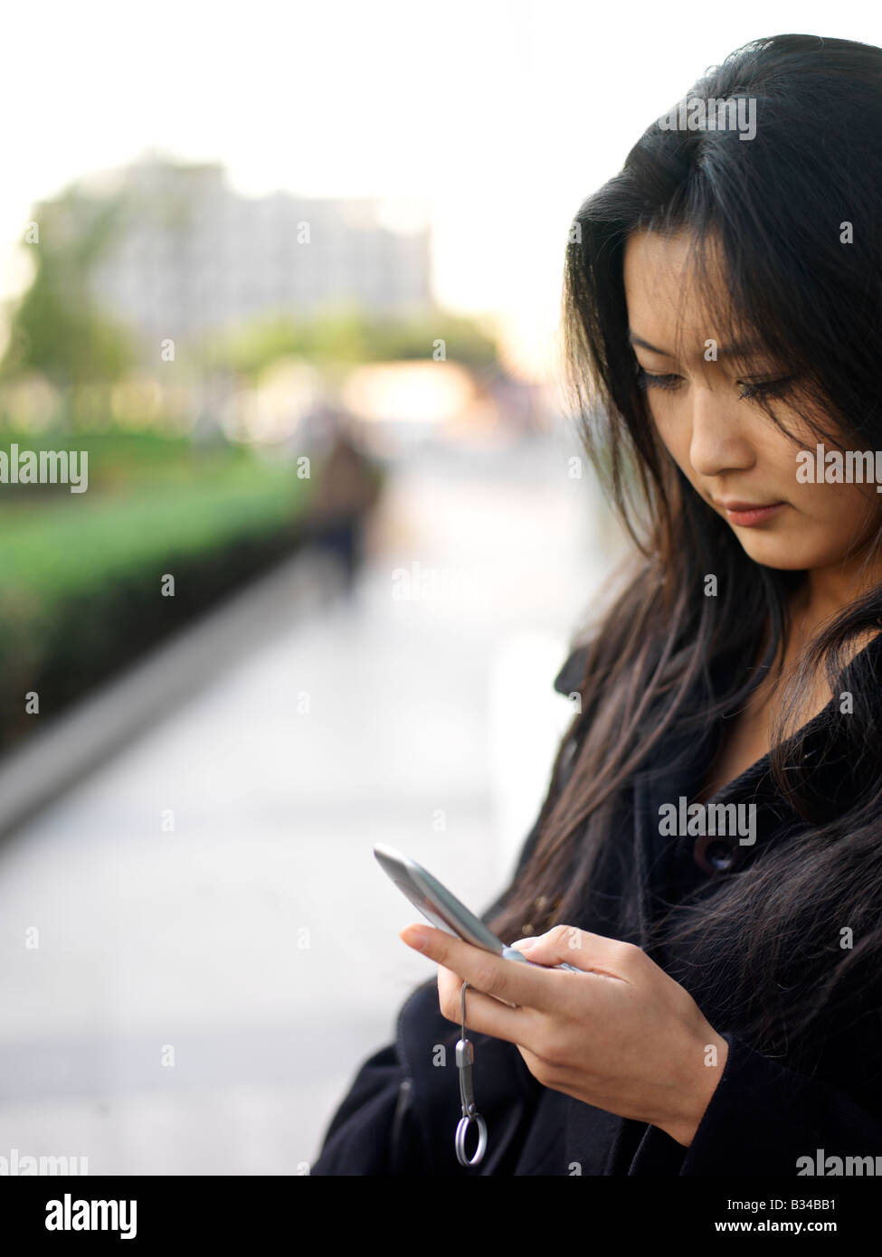 A young Chinese business woman using her mobile phone in the city Stock ...