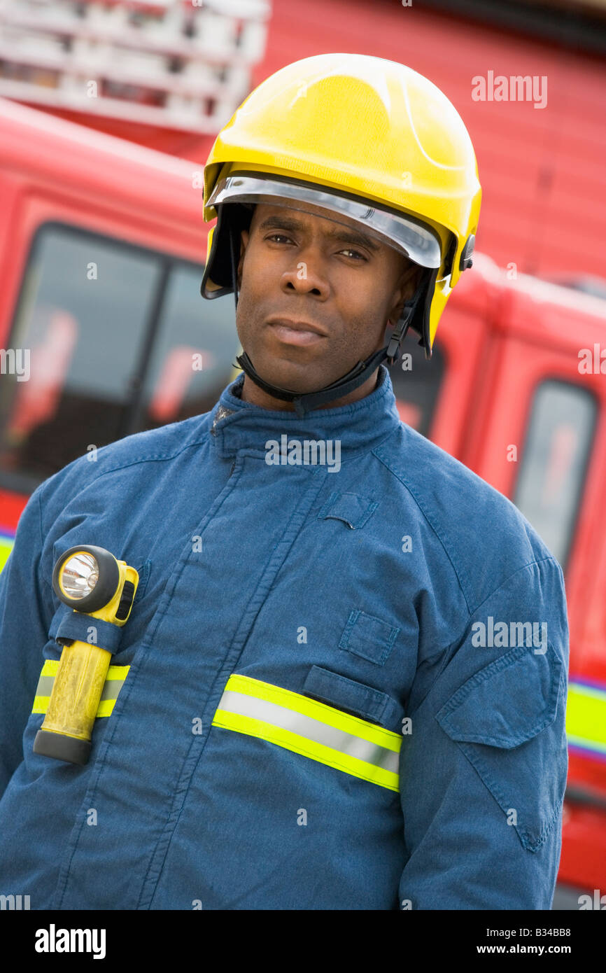 Fireman standing by fire engine wearing helmet Stock Photo - Alamy