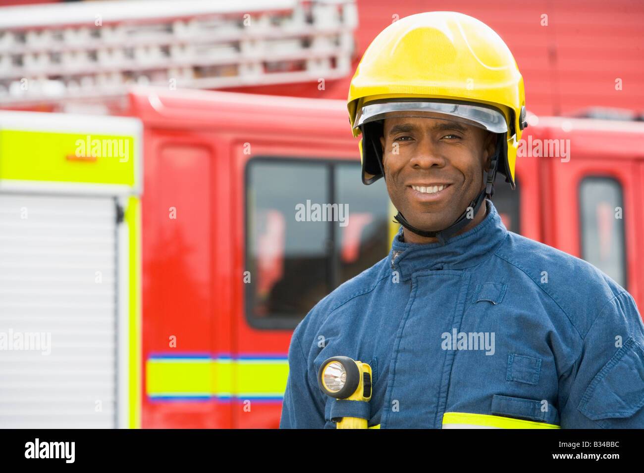 Fireman standing by fire engine wearing helmet Stock Photo - Alamy