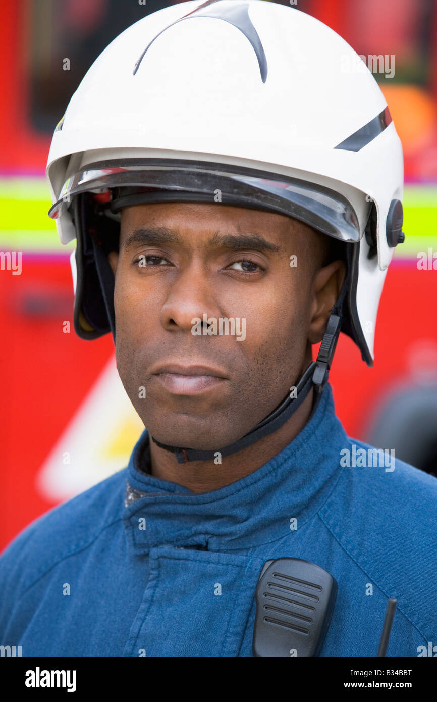Fireman standing by fire engine wearing helmet Stock Photo - Alamy