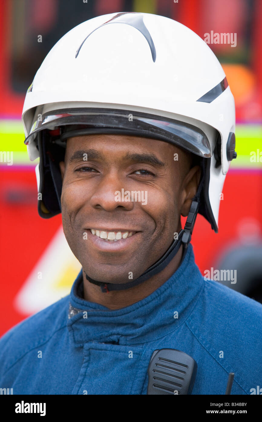 Fireman standing by fire engine wearing helmet Stock Photo - Alamy