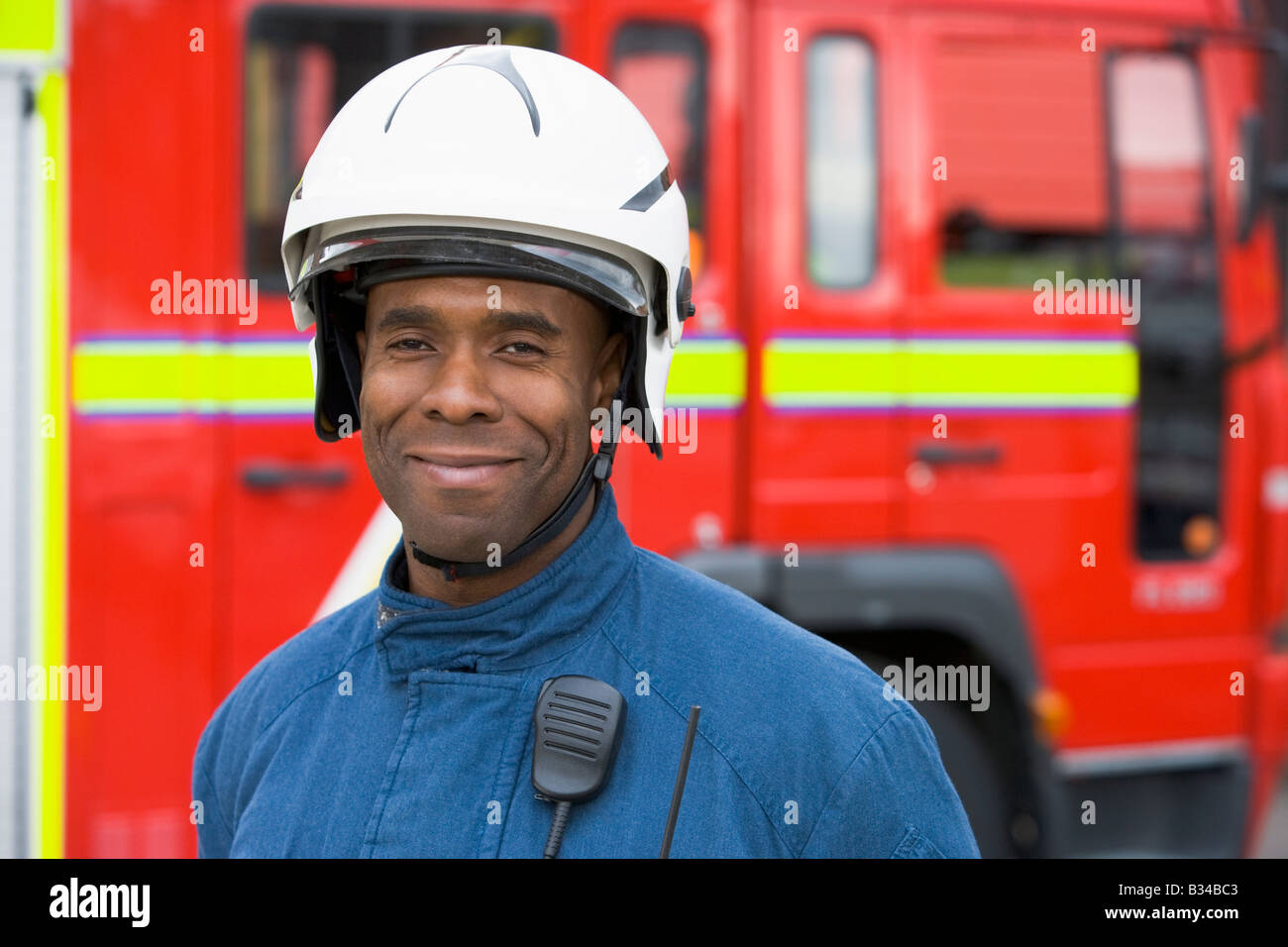 Fireman standing by fire engine wearing helmet Stock Photo - Alamy