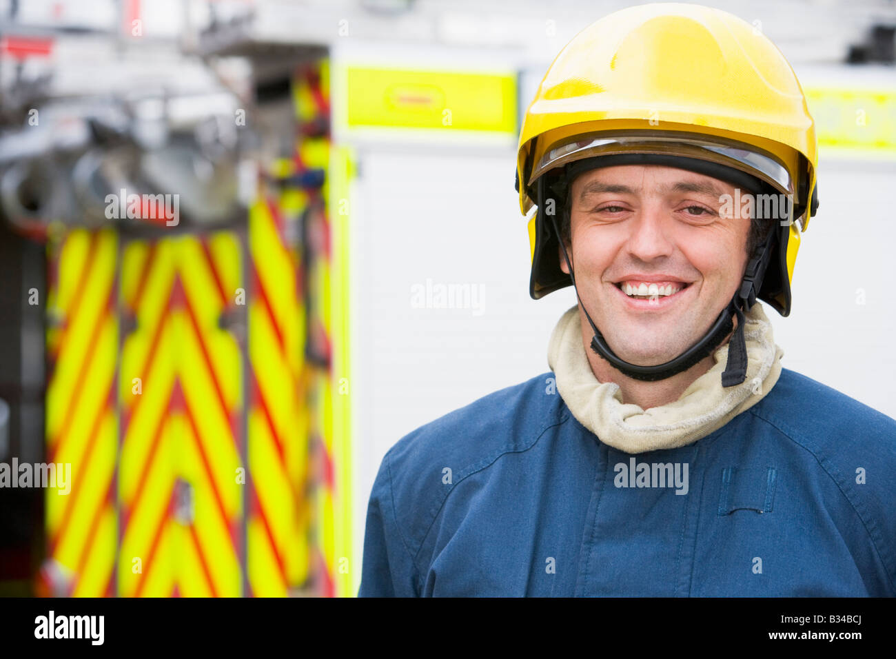 Fireman standing by fire engine wearing helmet Stock Photo - Alamy