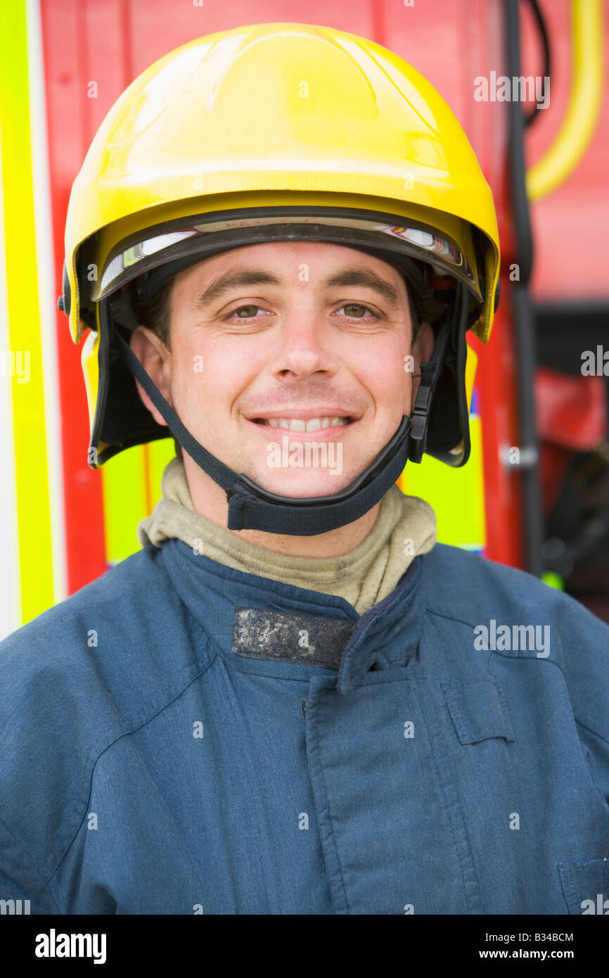 Fireman standing by fire engine wearing helmet Stock Photo - Alamy
