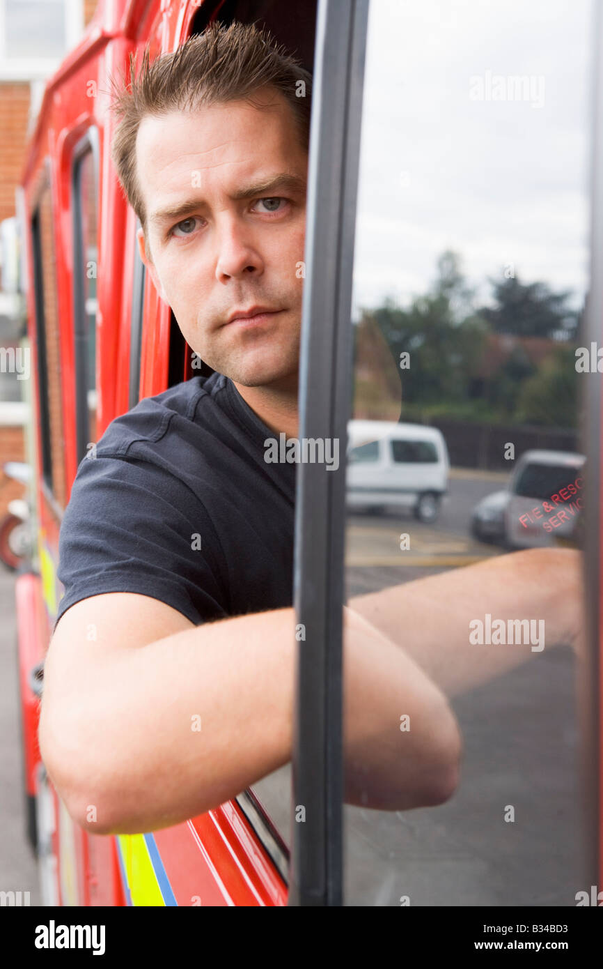 Fireman sitting in fire engine with head out window Stock Photo - Alamy