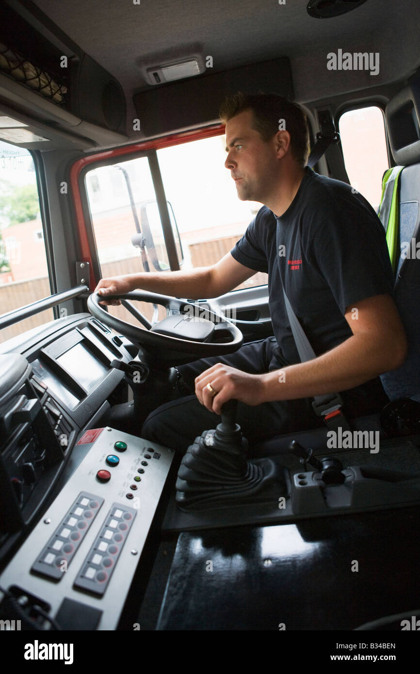 Fireman in fire engine holding steering wheel Stock Photo - Alamy