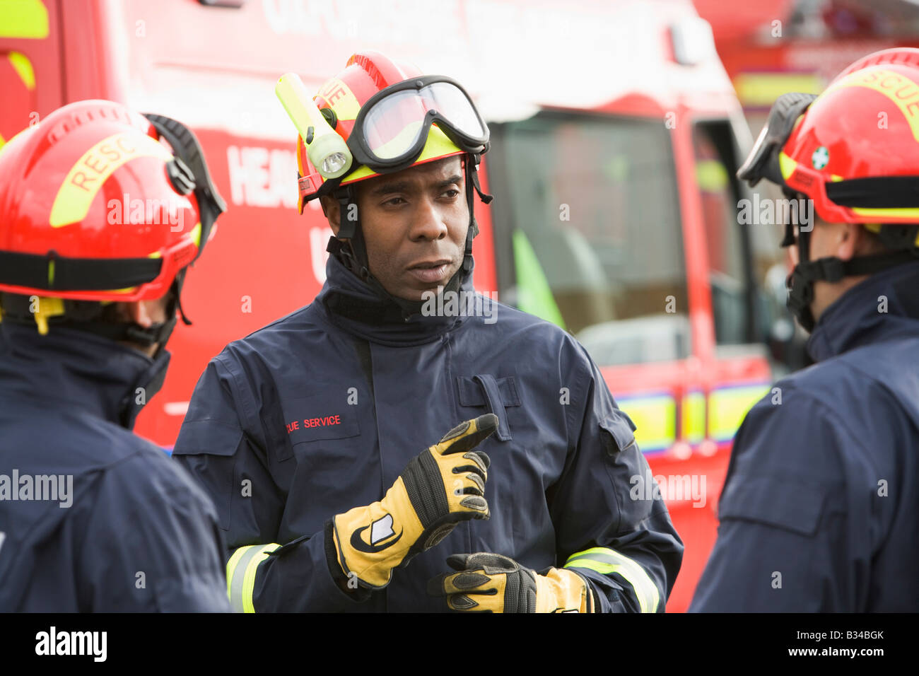 Three rescue workers talking by rescue vehicle (selective focus Stock ...