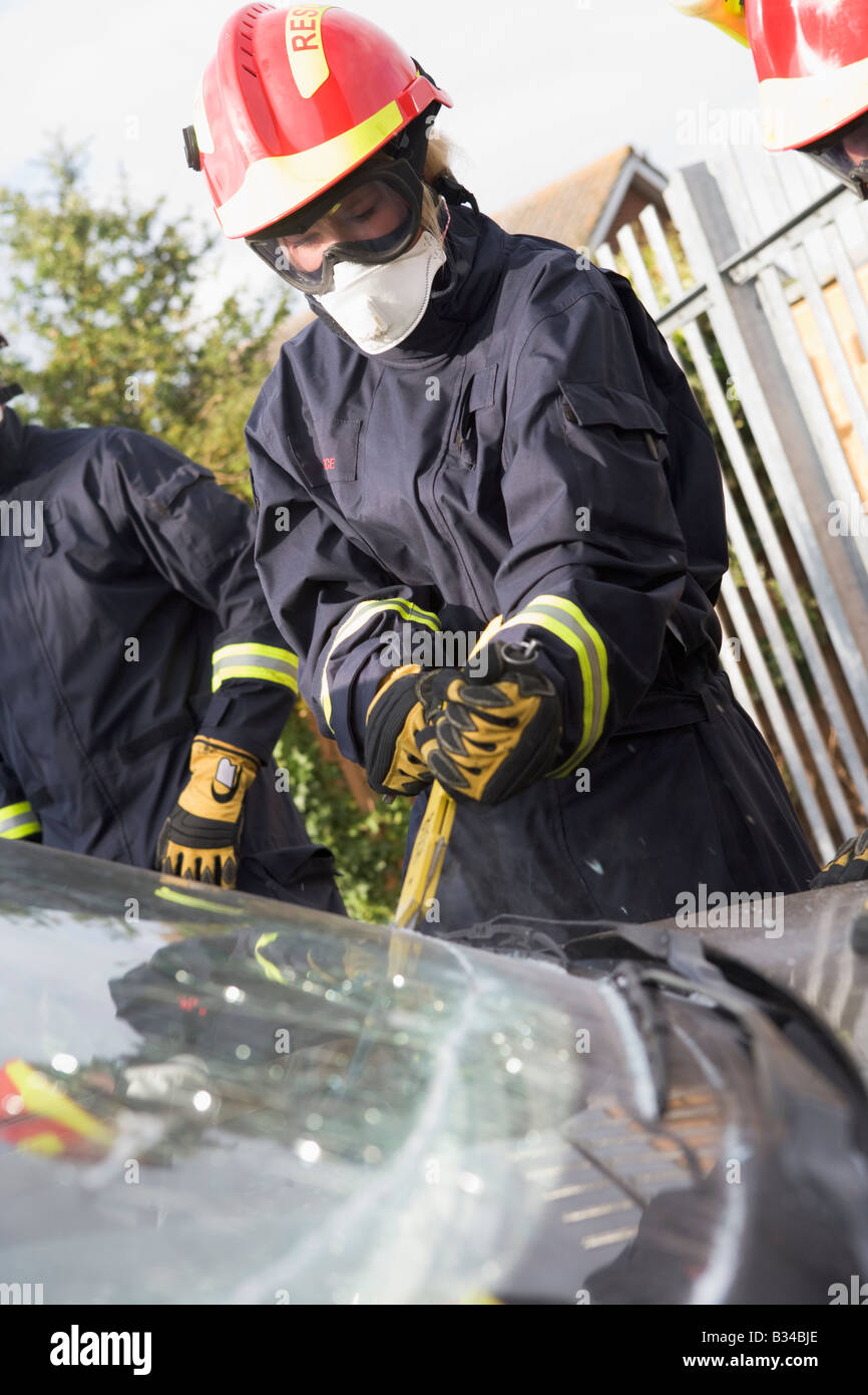 Two firefighters cutting out a windshield after an accident Stock Photo ...