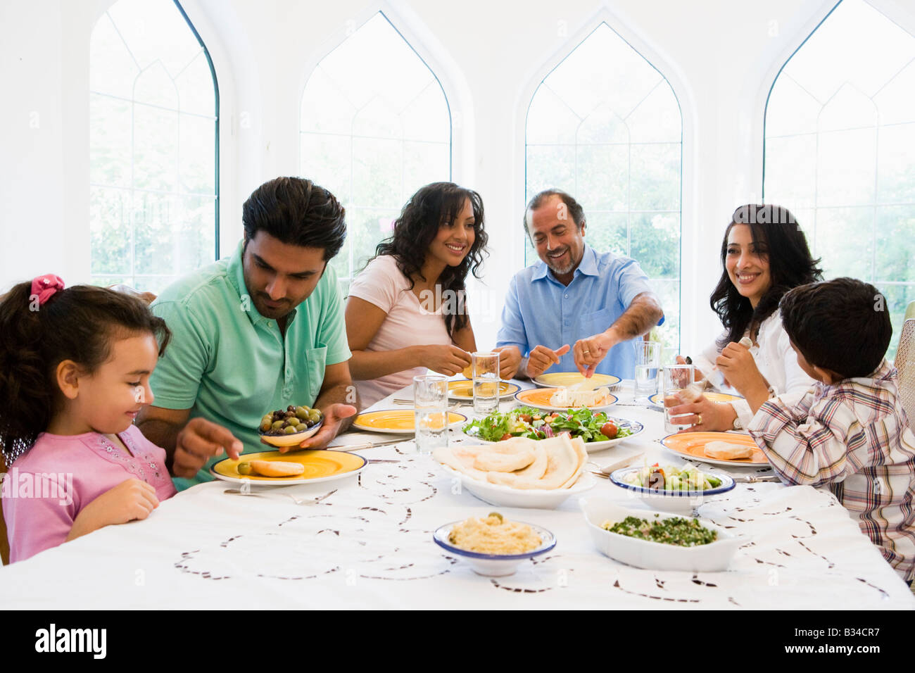 Family sitting at dinner table smiling (high key Stock Photo - Alamy