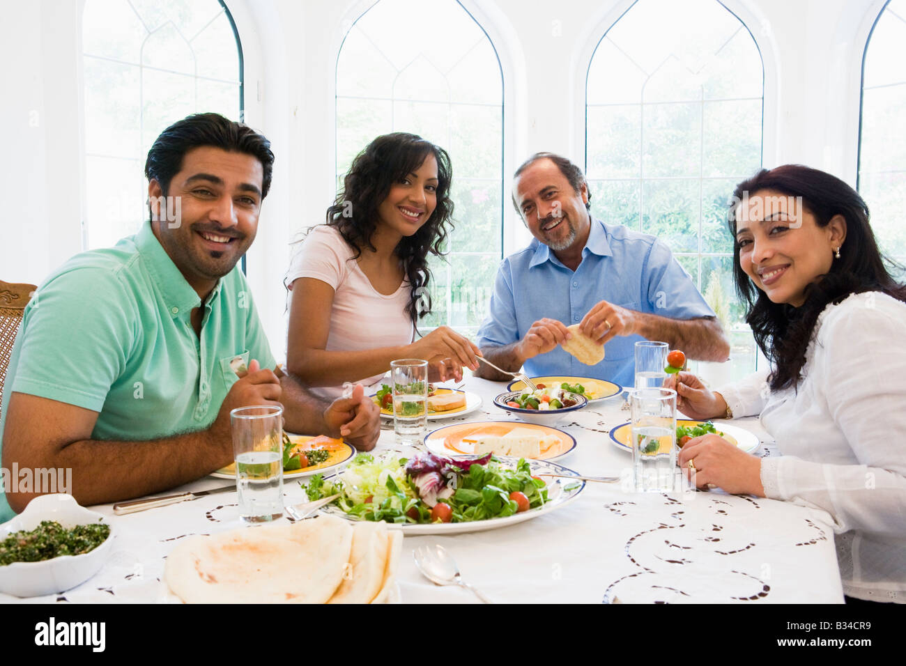 Two couples sitting at dinner table smiling (high key Stock Photo - Alamy