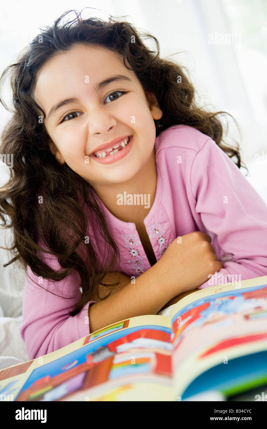 Young girl in living room with book smiling (high key/selective focus ...