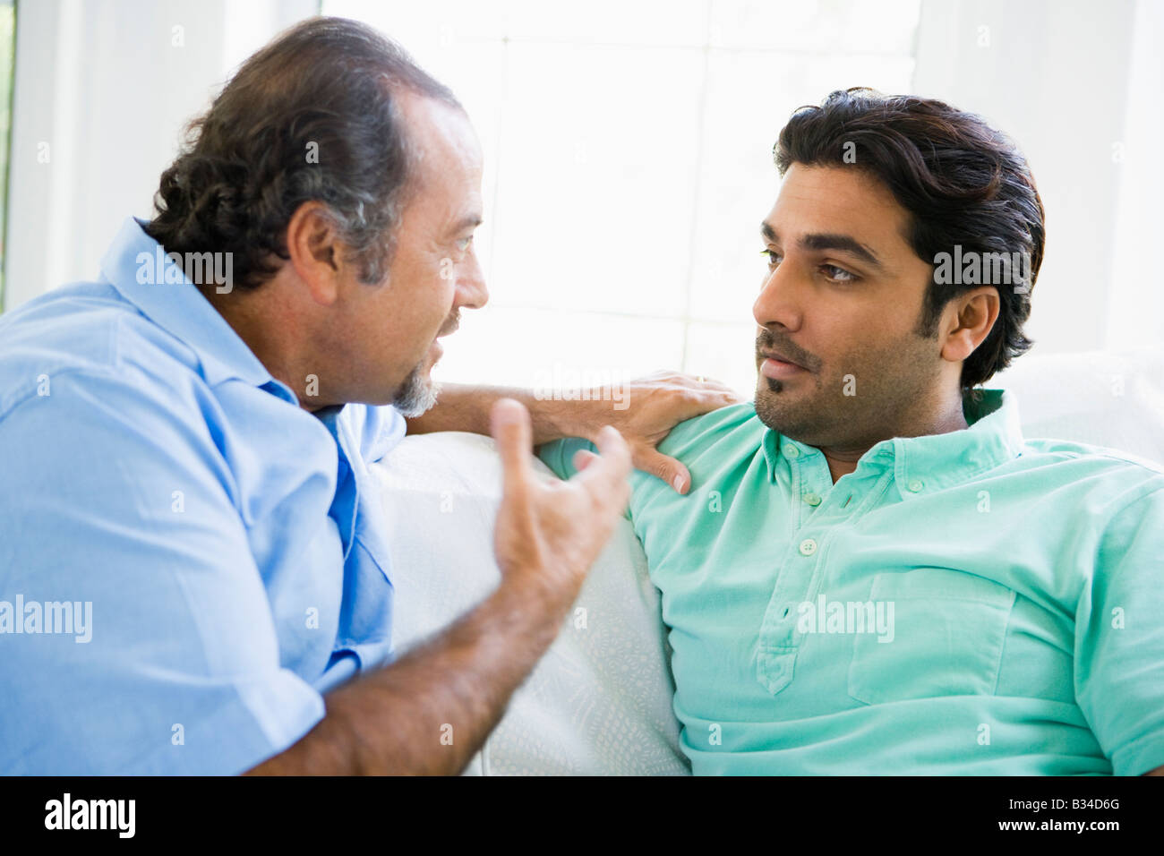 Two men in living room talking (high key Stock Photo - Alamy