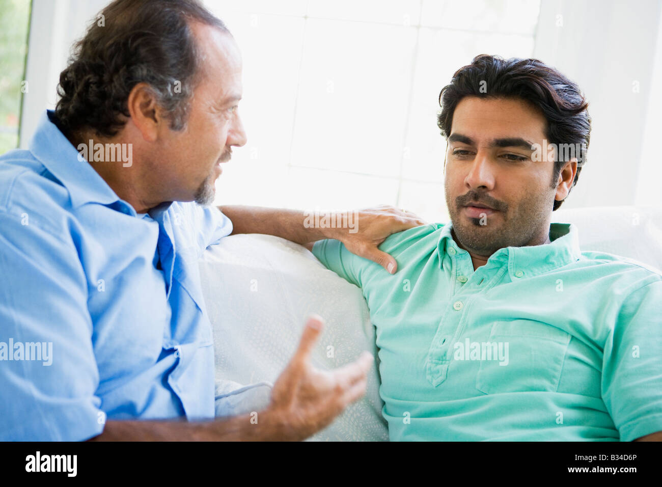 Two men in living room talking (high key Stock Photo - Alamy