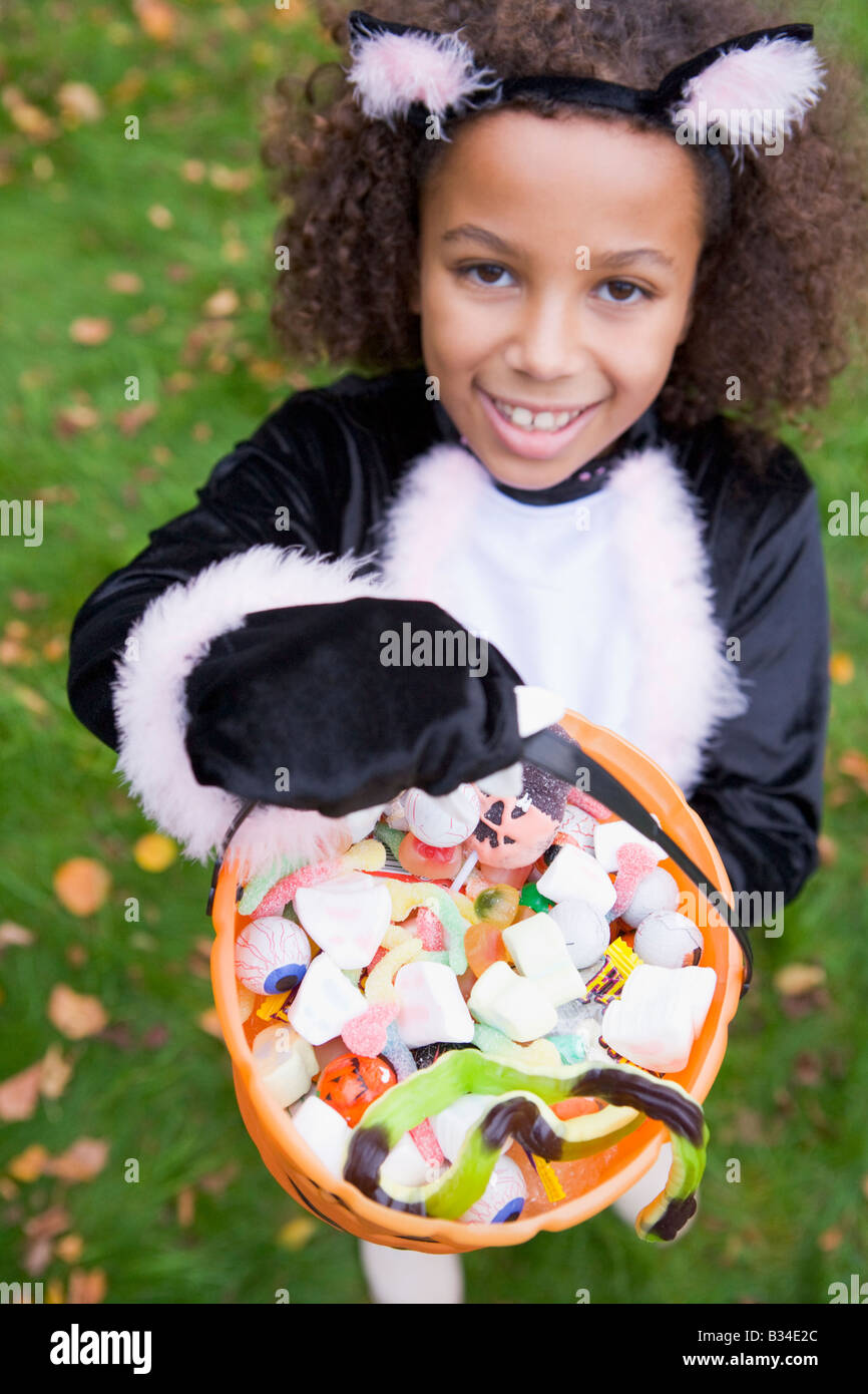 Young girl outdoors in cat costume on Halloween holding candy Stock ...